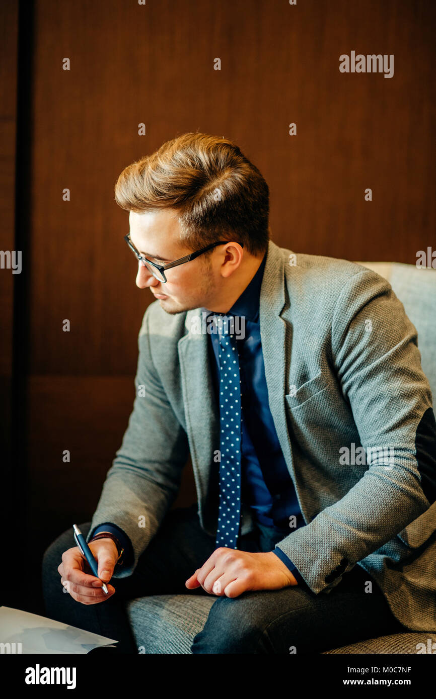 man is preparing for interview. He in suit, sitting in hall on chair ...