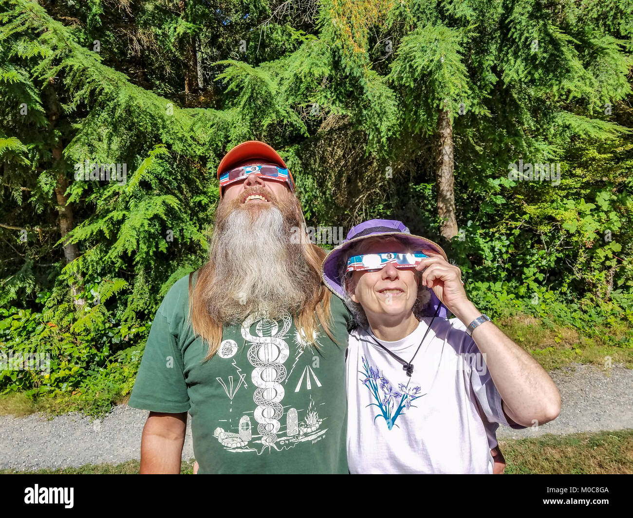 Man and woman watch the solar eclipse begin using protective glasses ...