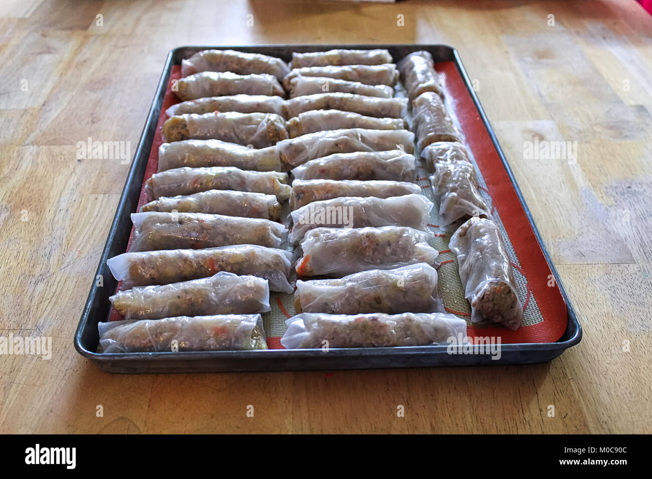 A tray of rice wrapped spring rolls on a cookie sheet Stock Photo - Alamy