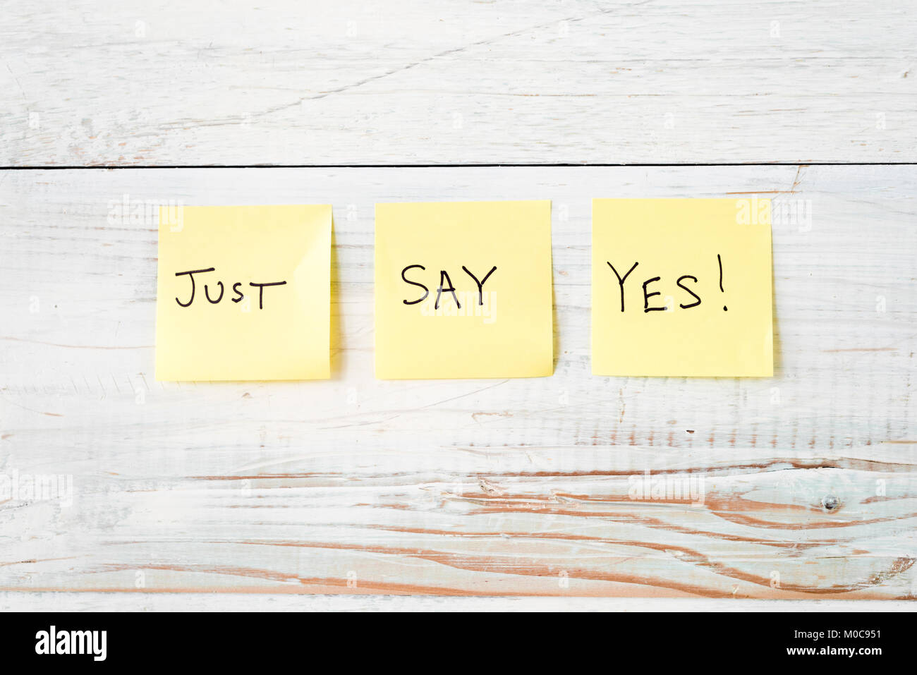 three yellow Post It notes with message Just Say Yes! against weathered ...
