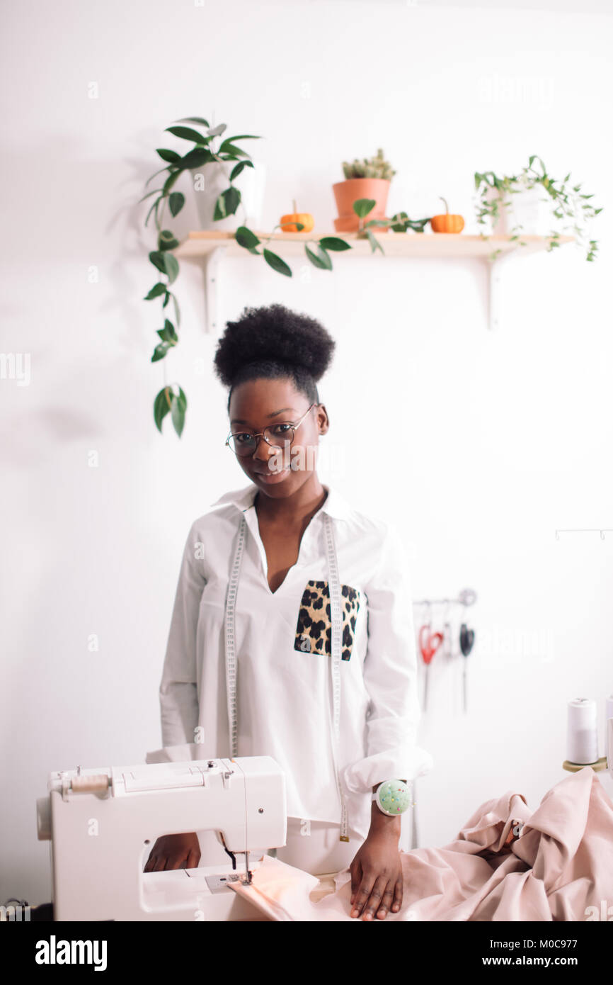 smiling seamstress looking at camera with sewing machine Stock Photo ...