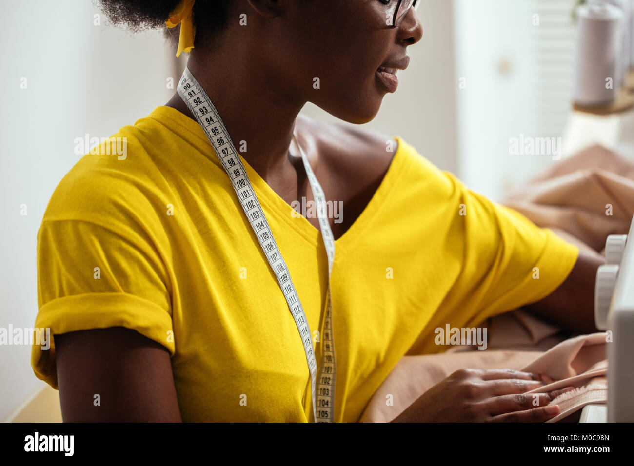 smiling seamstress looking at camera with sewing machine Stock Photo ...