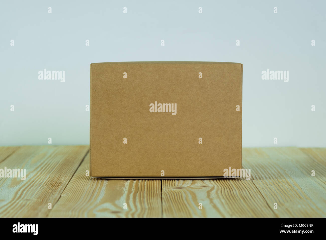 Empty closed brown cardboard box for mock up on bright wooden table ...
