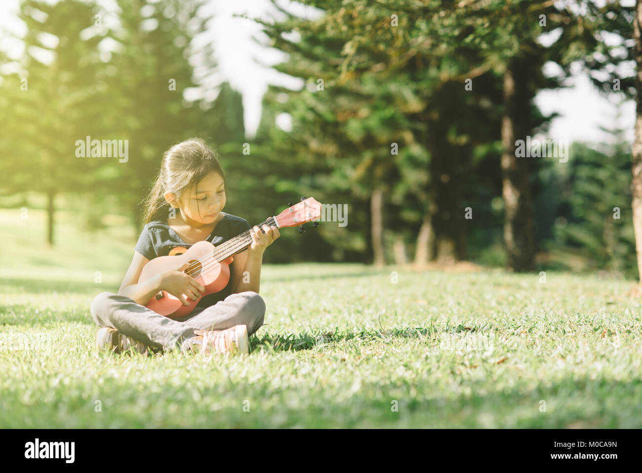 Young And Happy Asian Girl Playing With Ukelele Guitar At The Park In