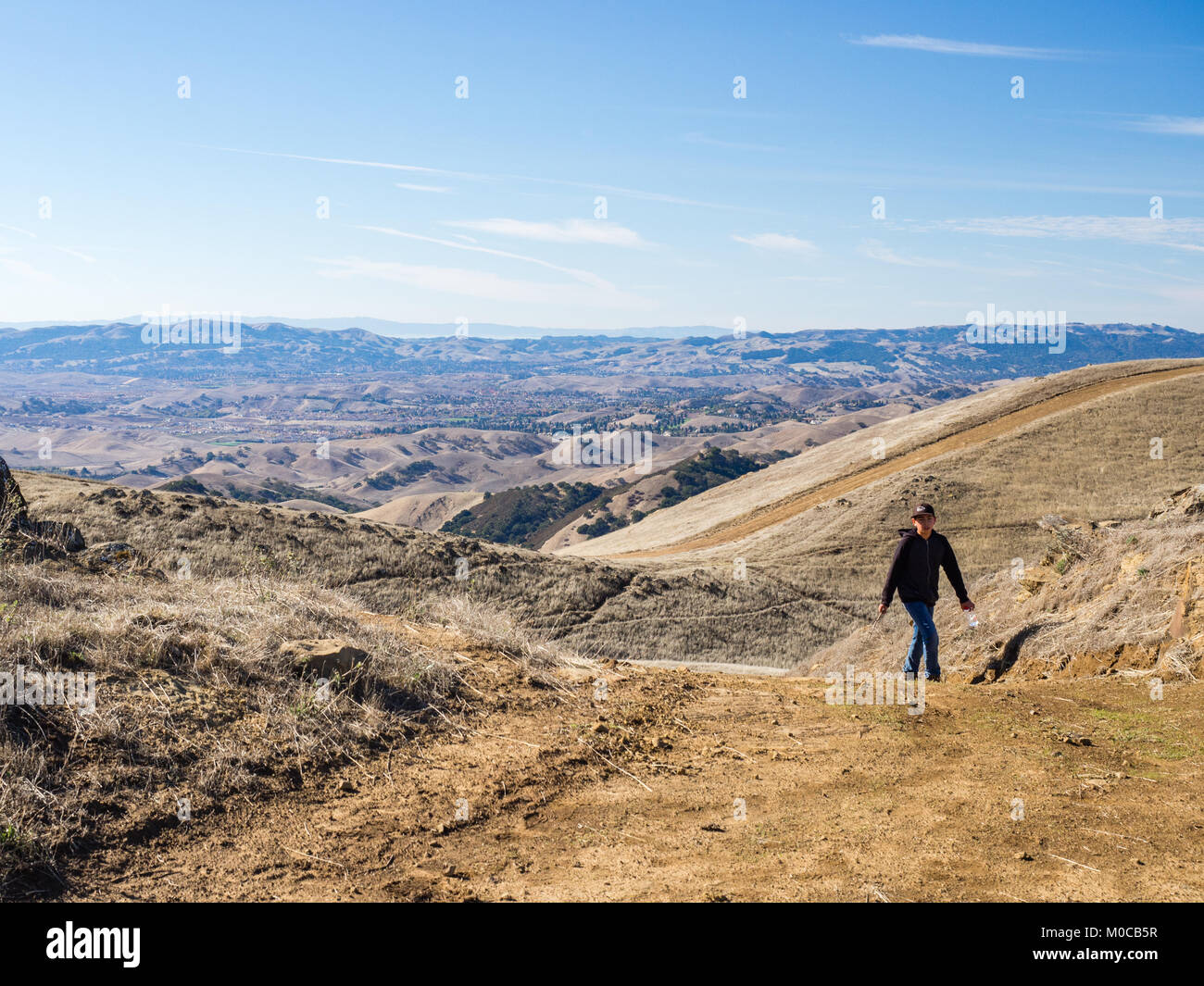 10 year old boy hiking on remote golden, grassy hill in California with ...