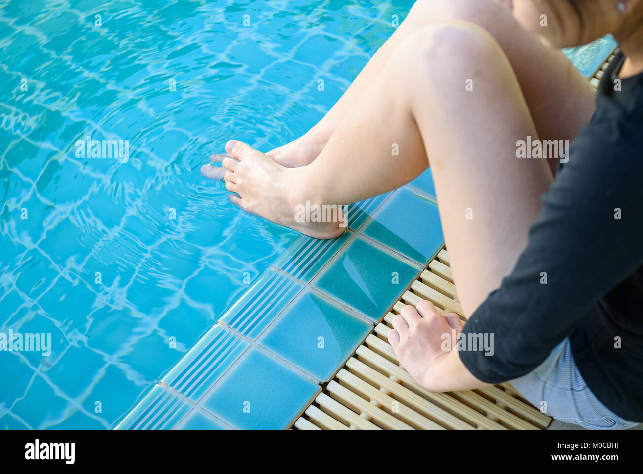 Woman dipping feet in pool hi-res stock photography and images - Alamy