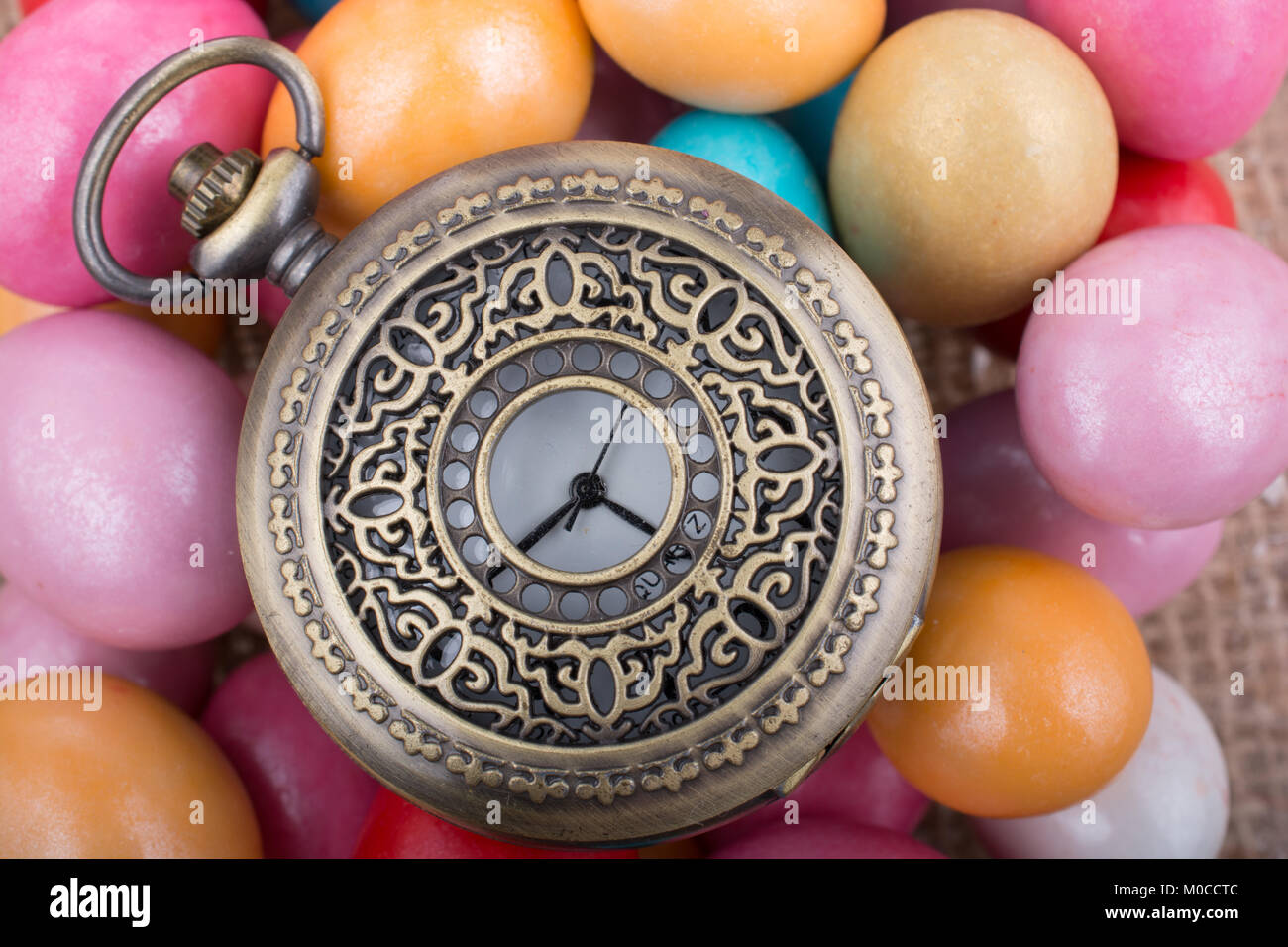 Mechanical pocket watch on colorful candy sweets Stock Photo - Alamy