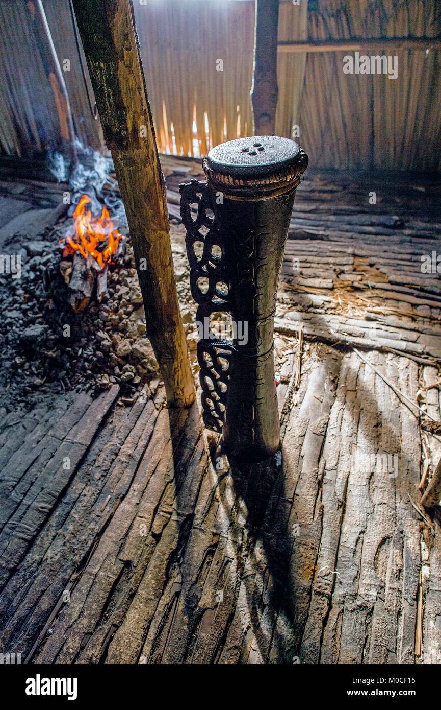 Ritual drum Asmat tribe at the fire in a ceremonial man's house of ...