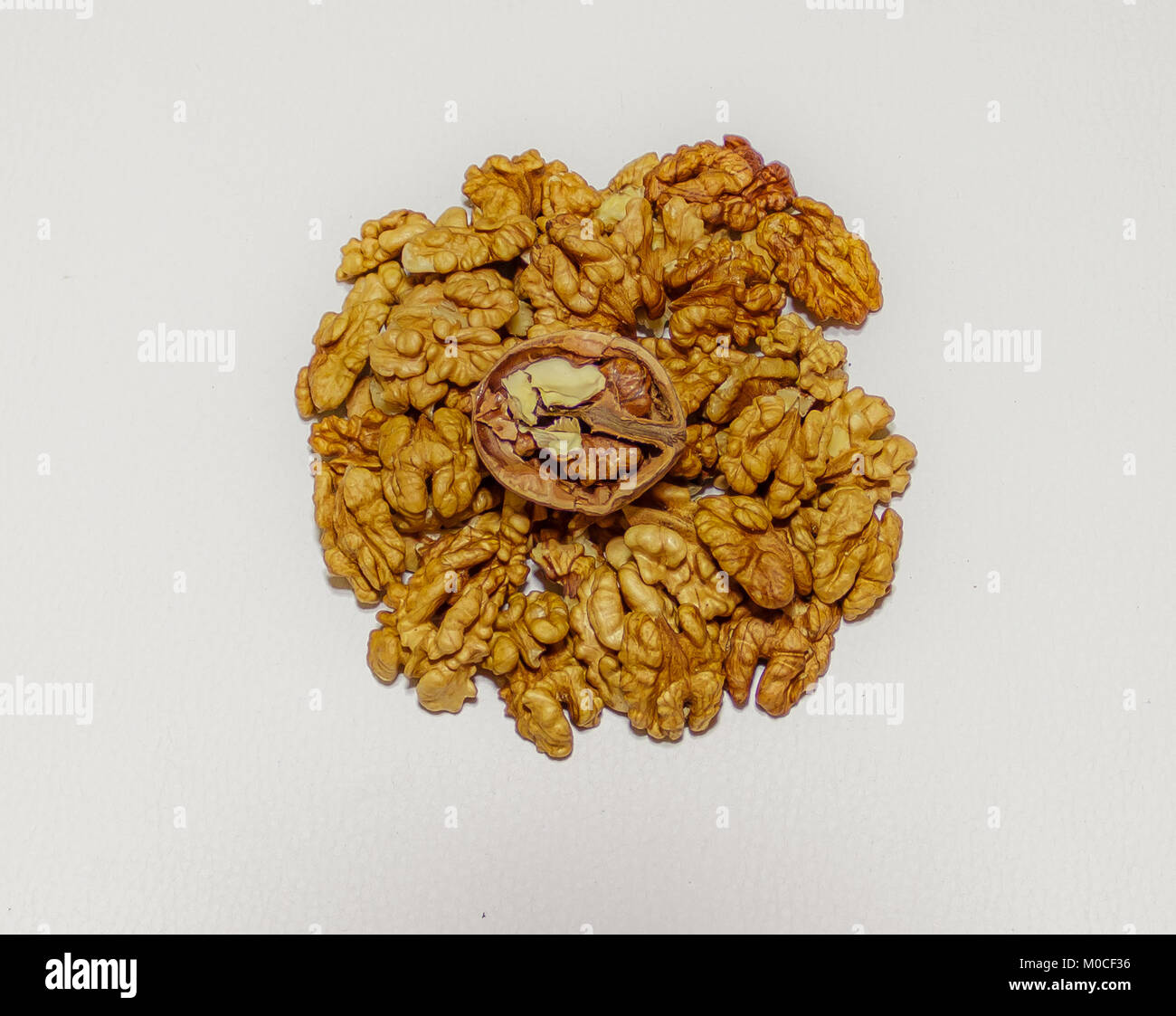 A pile of walnut kernels and cracked walnut on the top on white ...