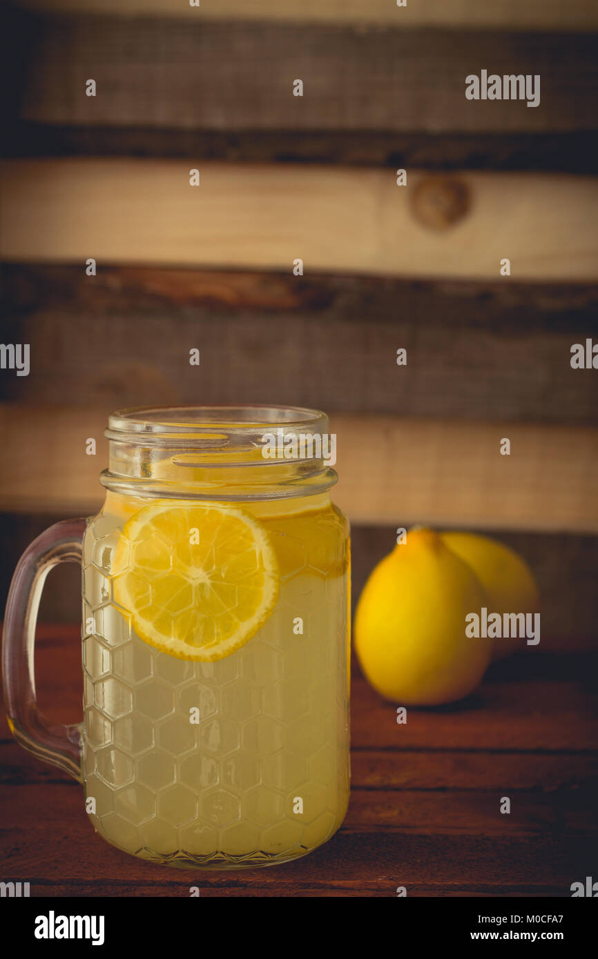 Fresh lemonade in mason jar and lemons on wooden background Stock Photo ...