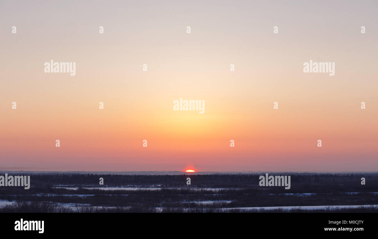 Crimson winter sun in zenith, clear sky. Natural vibrant cold colors ...