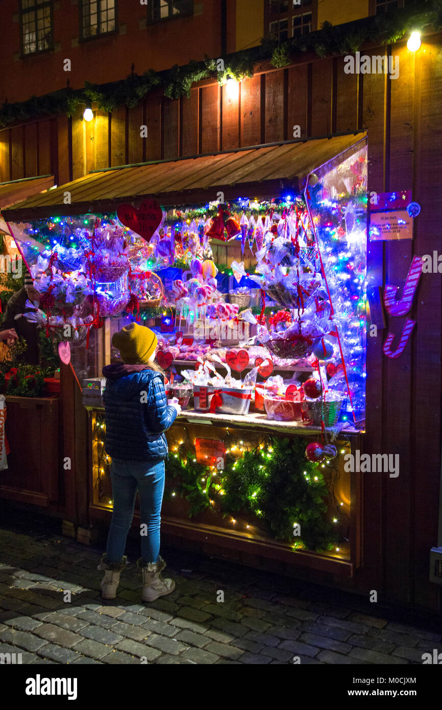 A child standing in front of a candy cane and sweets booth at a ...