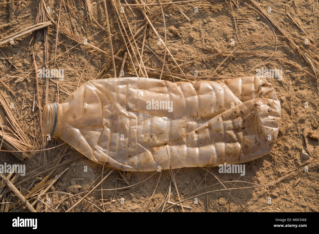 Empty plastic bottle covered in dirt on ground Stock Photo - Alamy