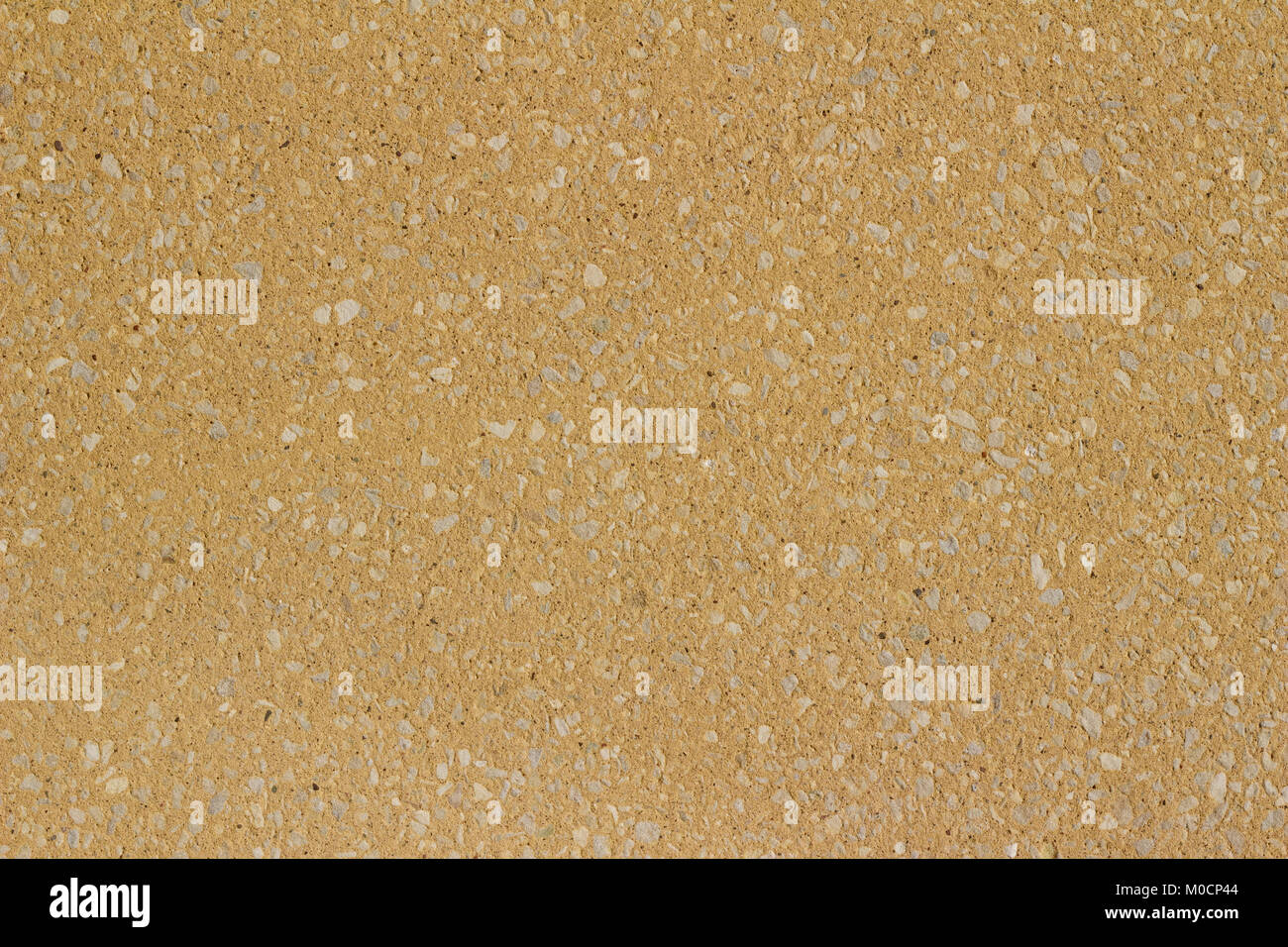 Sand colored tan stucco wall background with exposed stones on its ...