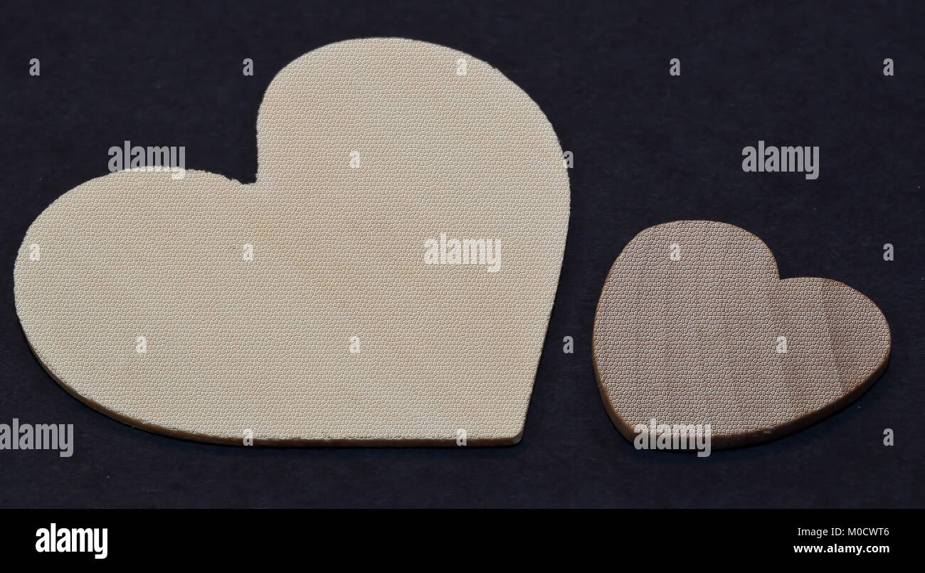 Two wooden hearts, a larger one along with a smaller one on a black ...