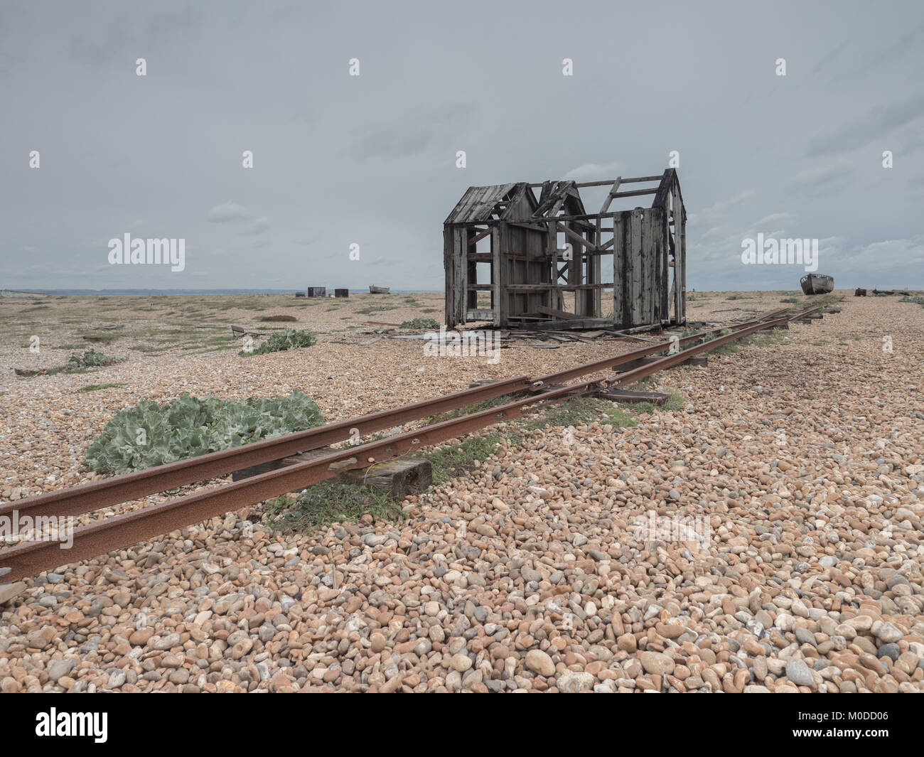 Weathered and broken shack beside rusty rails on shingle beach at ...