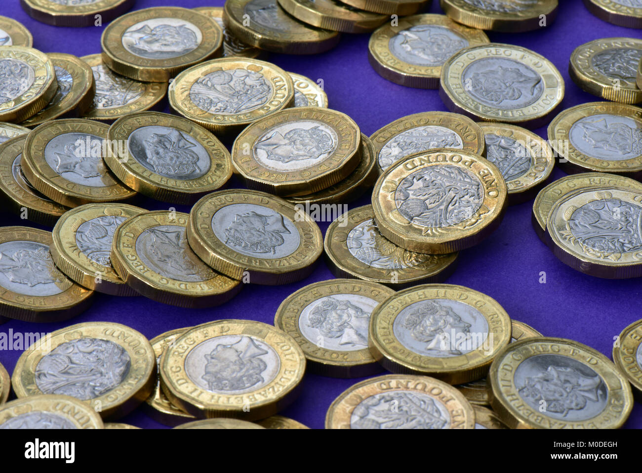 a large number of one pound coins on a colourful background. gold and ...