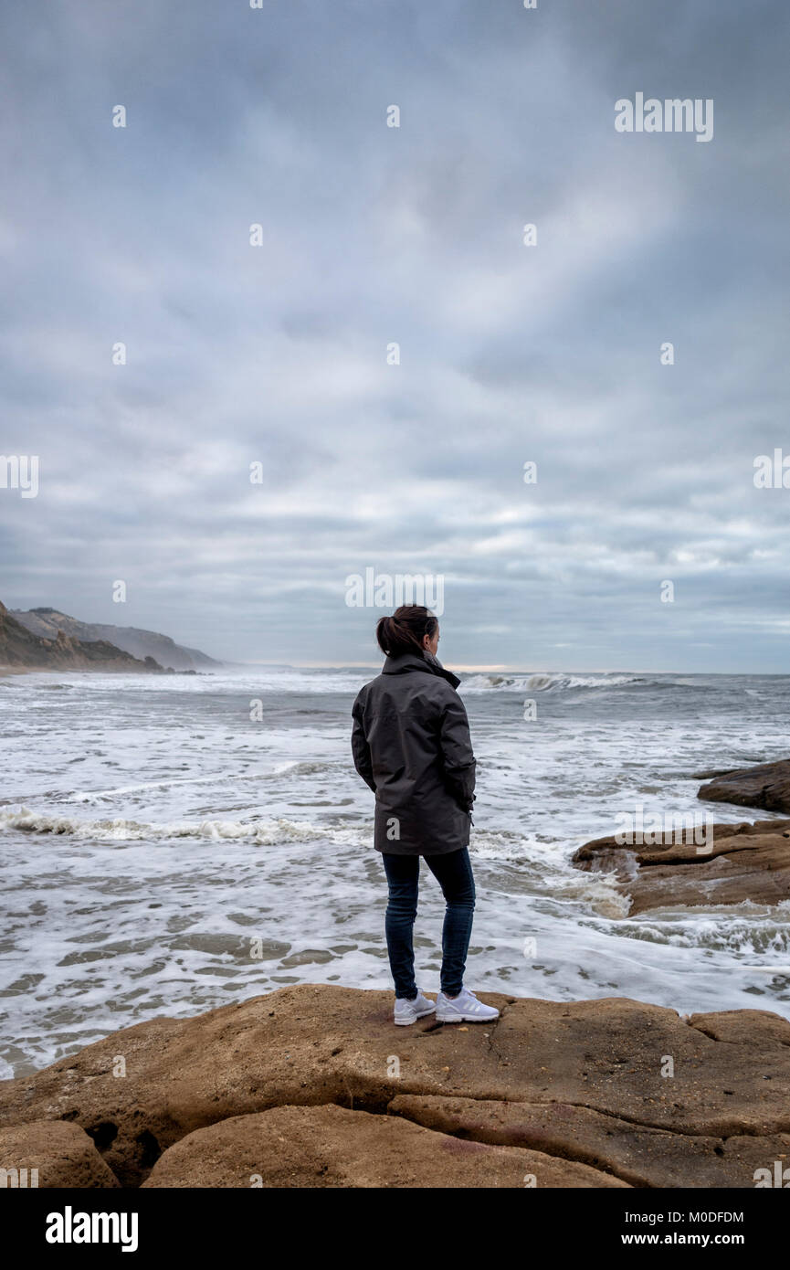 woman hiker standing on rocks looking out over the ocean Stock Photo ...