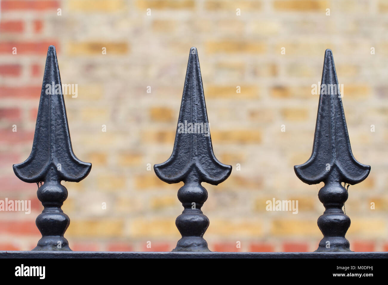 horizontal front view of black painted iron fence spikes in front of a ...