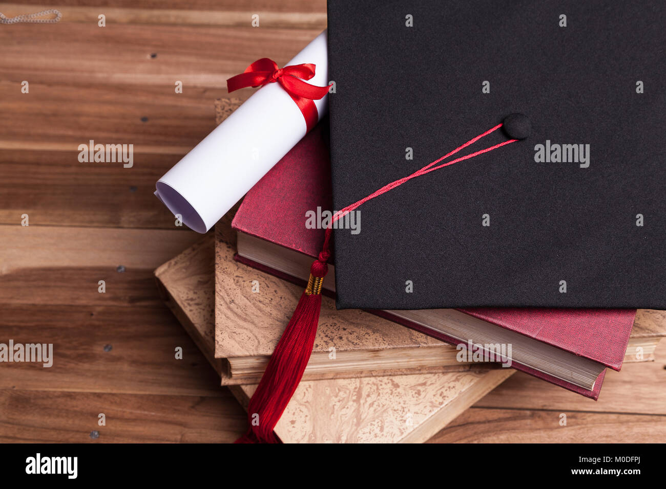 Black graduation cap and diploma on a stack of books Stock Photo - Alamy