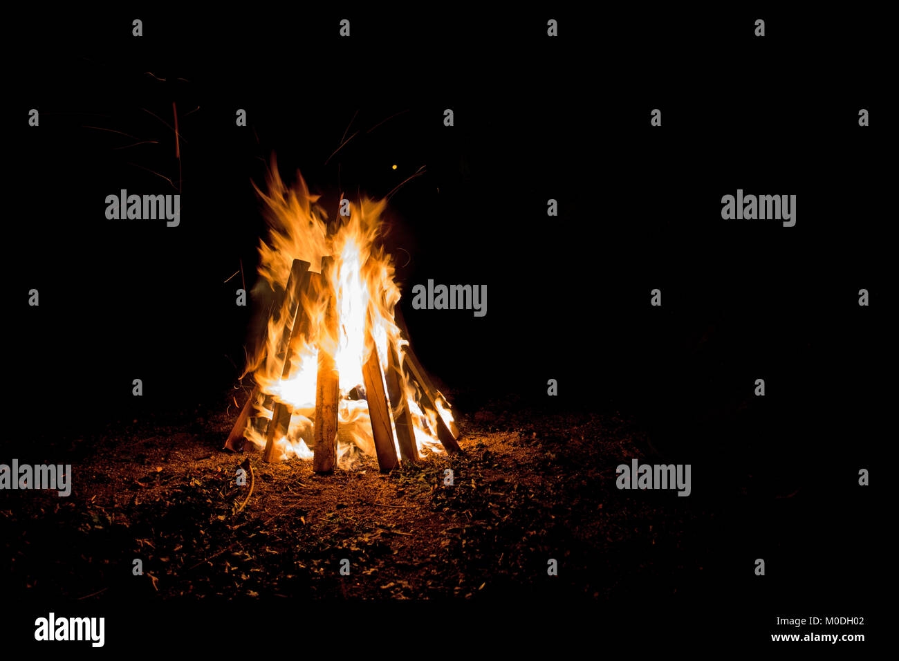 An outdoor bonfire with tall flames contained in boards shaped like a ...
