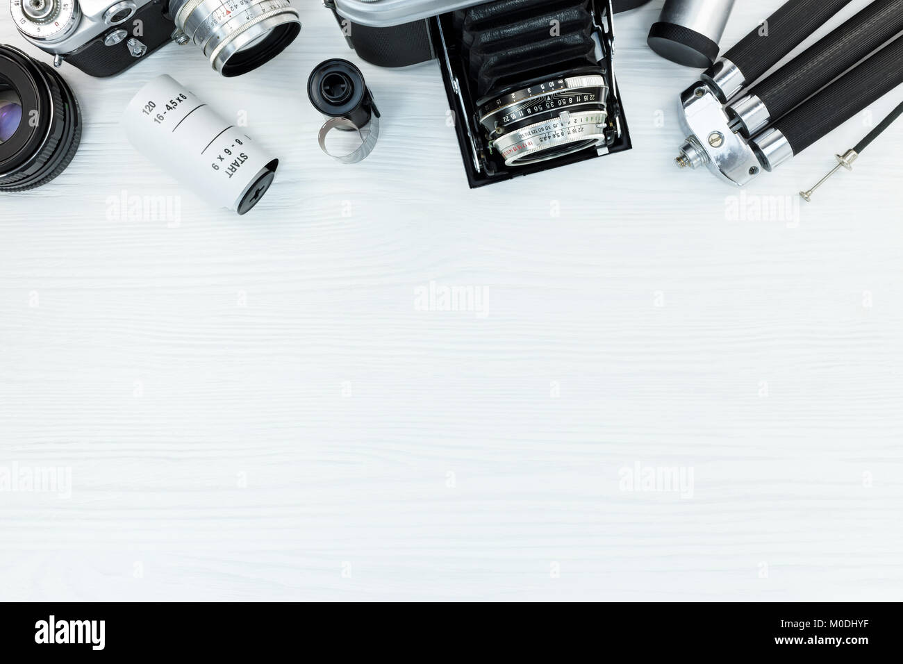 vintage photo cameras, negative films, lens and tripod on white table ...