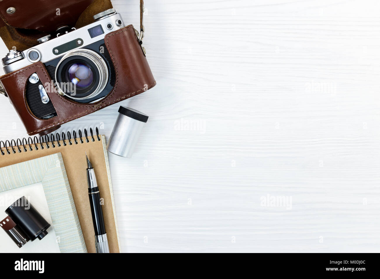old retro camera in leather cover, notebook, pen, and roll film on ...
