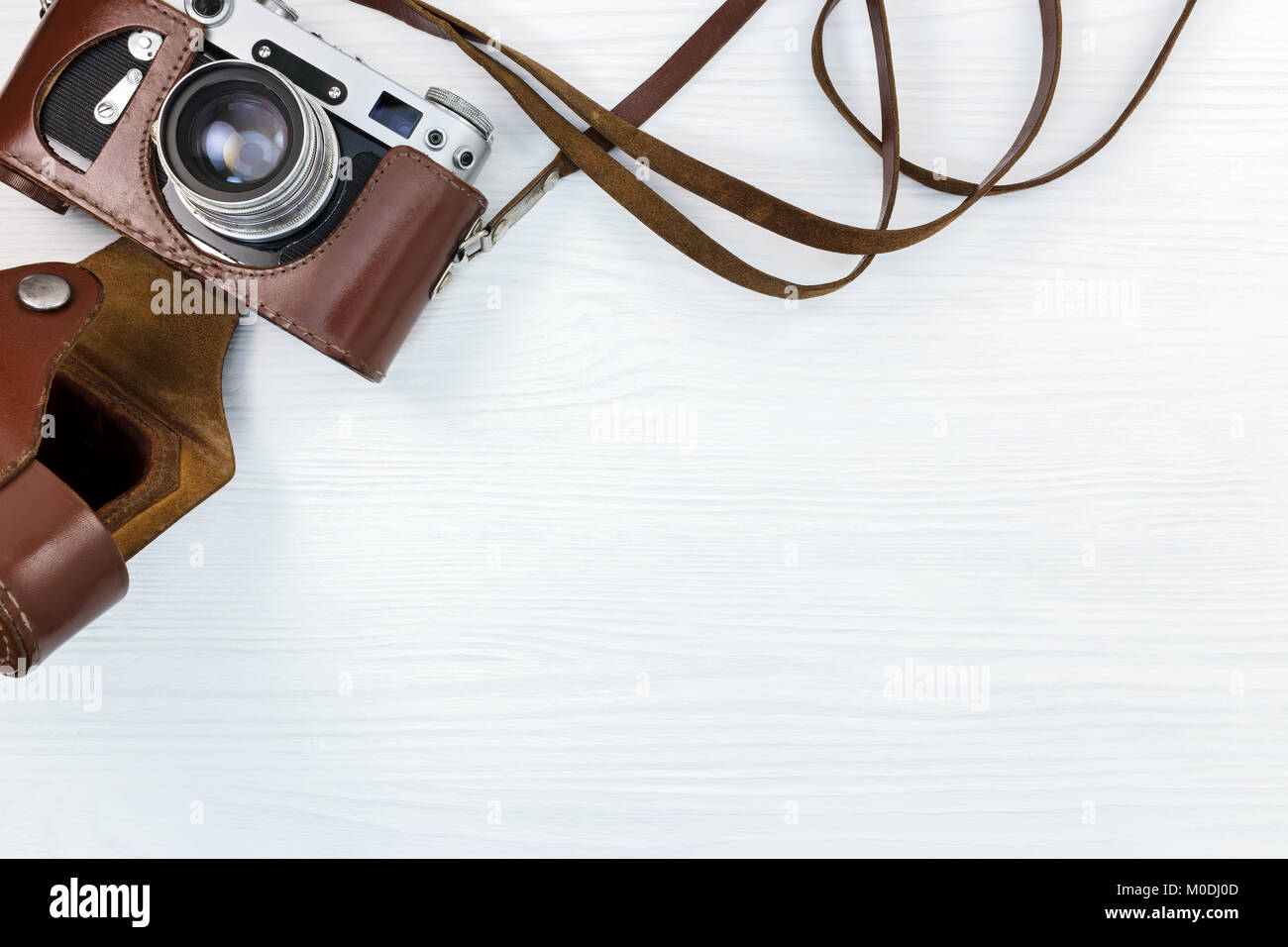 old classic photo camera in brown leather case on white wooden surface ...