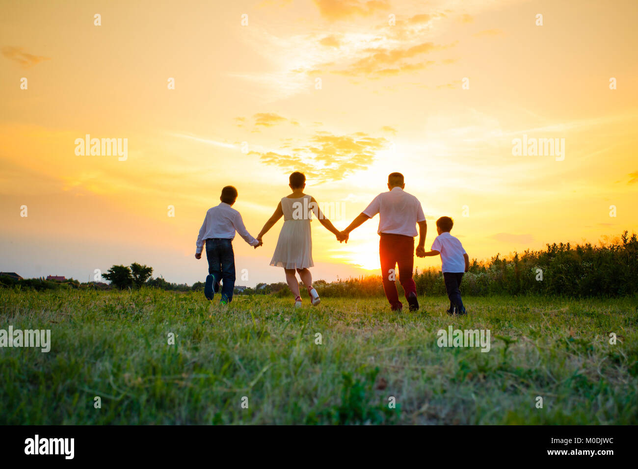Happy family on the background of the sunset Stock Photo - Alamy