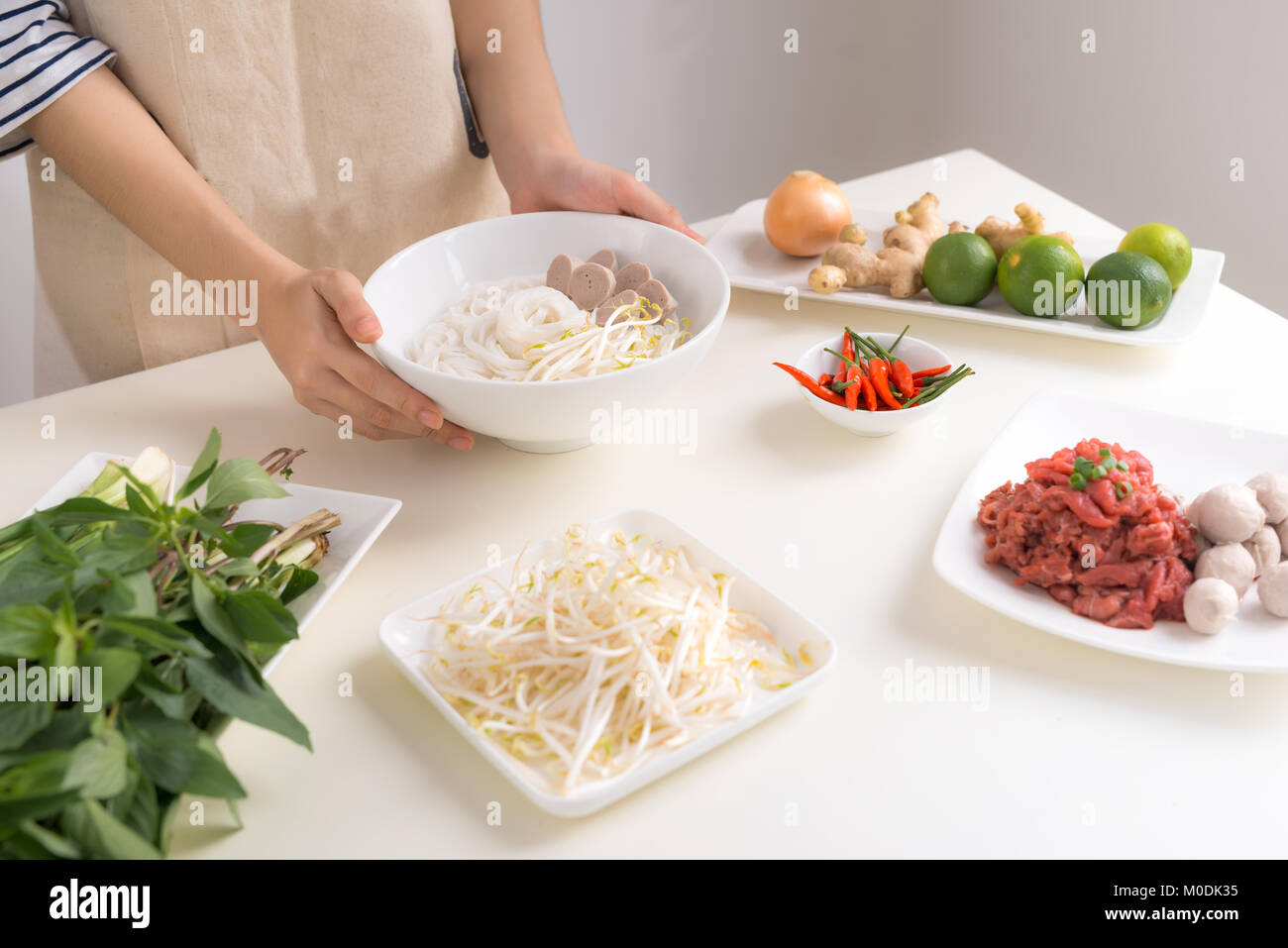 Female chef prepare traditional Vietnamese soup Pho bo with herbs, meat ...