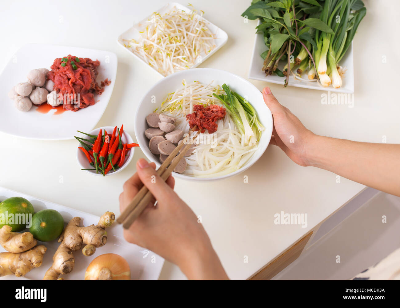 Female chef prepare traditional Vietnamese soup Pho bo with herbs, meat ...