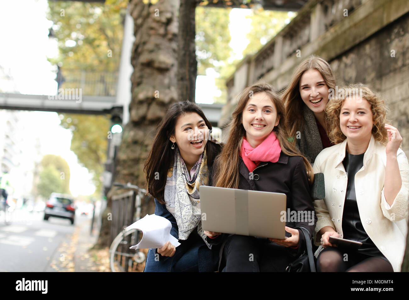 Female students sitting on bench and learning with laptop and pa Stock ...
