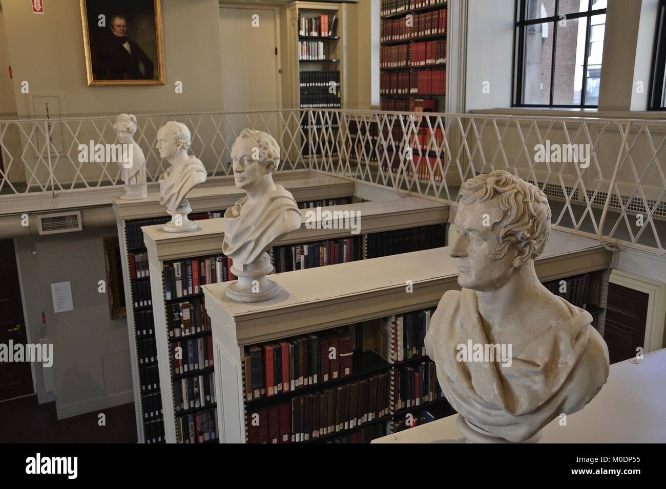 Busts of historical figures atop bookshelves in the Boston Athenaeum ...