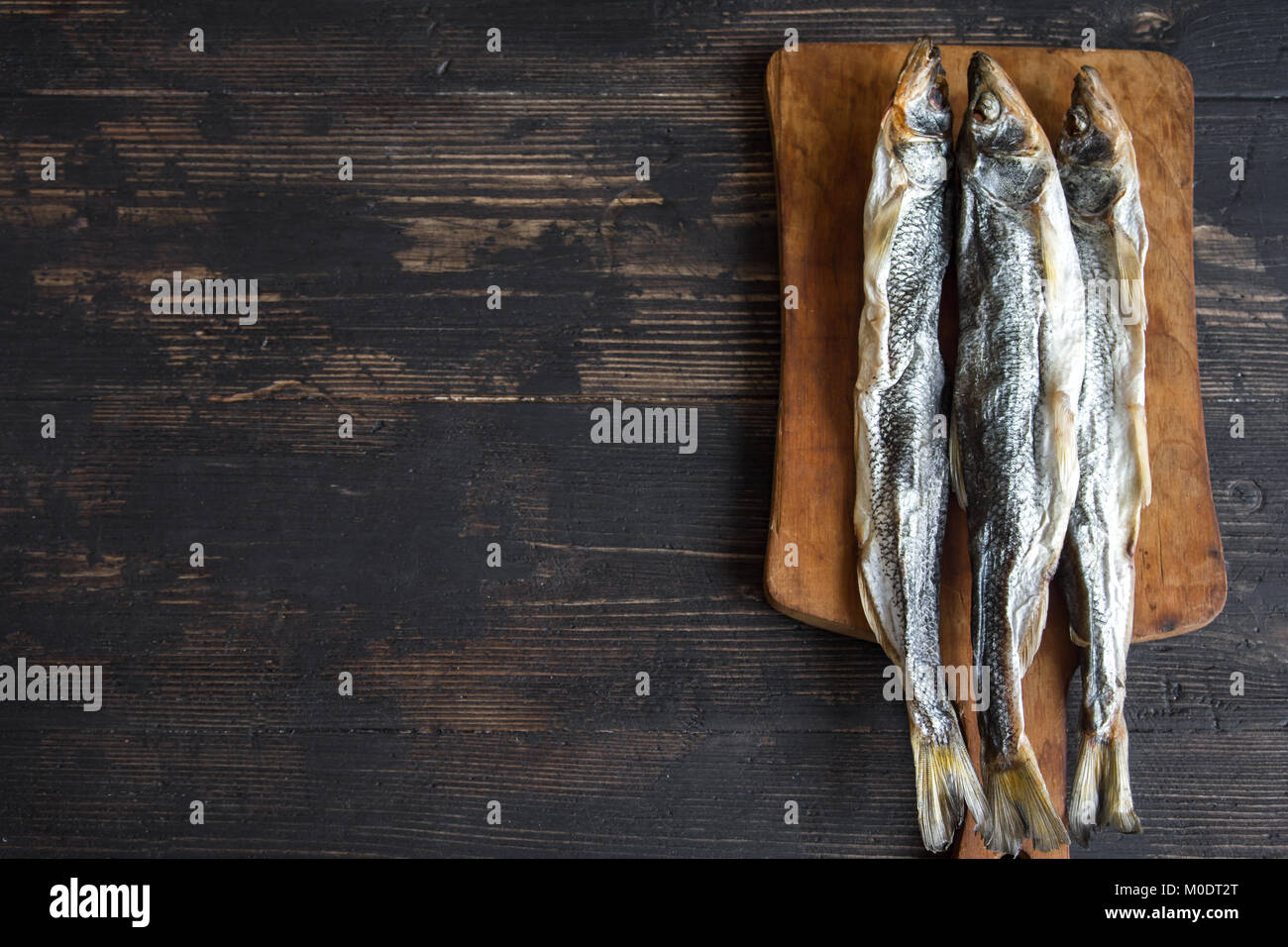 Sun dried fish, salted smelts over wooden background, top view, copy ...
