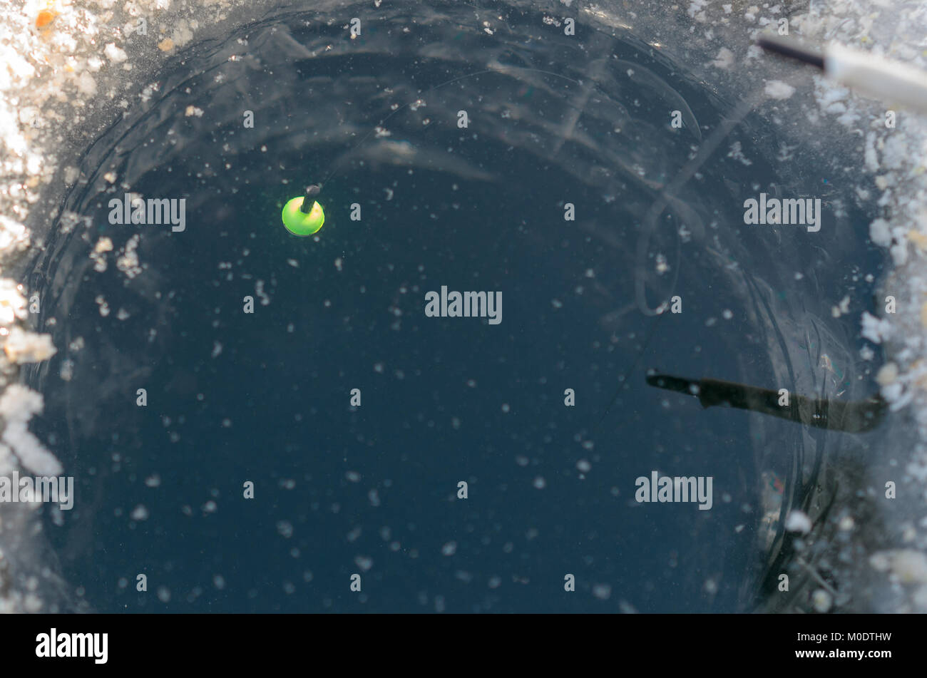 Round ice in the ice with a float on the line Stock Photo - Alamy