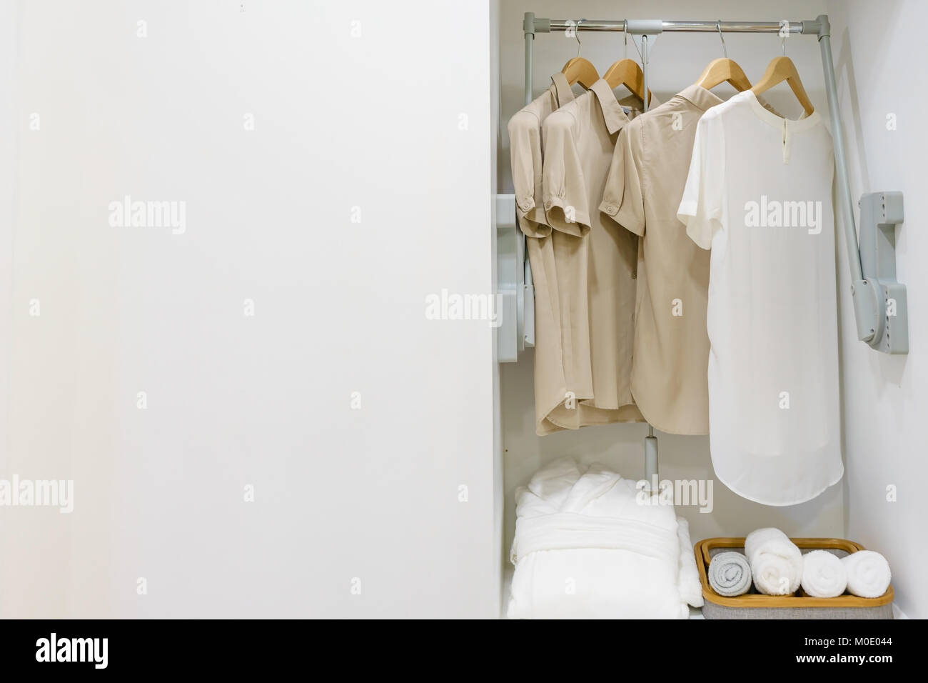 modern wooden wardrobe with clothes hanging on rail in walk in closet ...