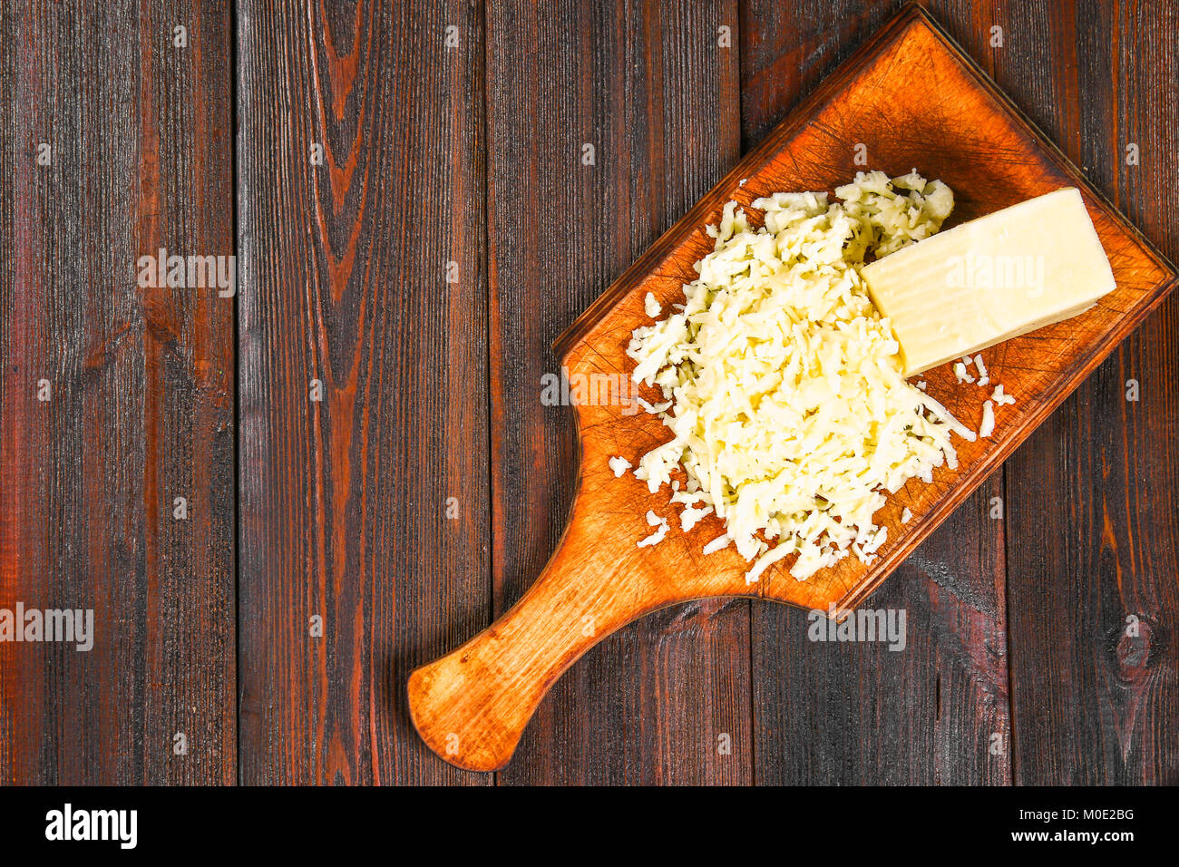 Portion of grated Cheddar Cheese on rustic wooden table Stock Photo - Alamy