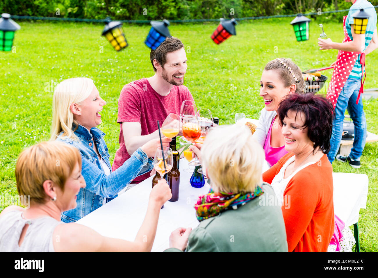 People toasting at party, in the background man at grill Stock Photo ...