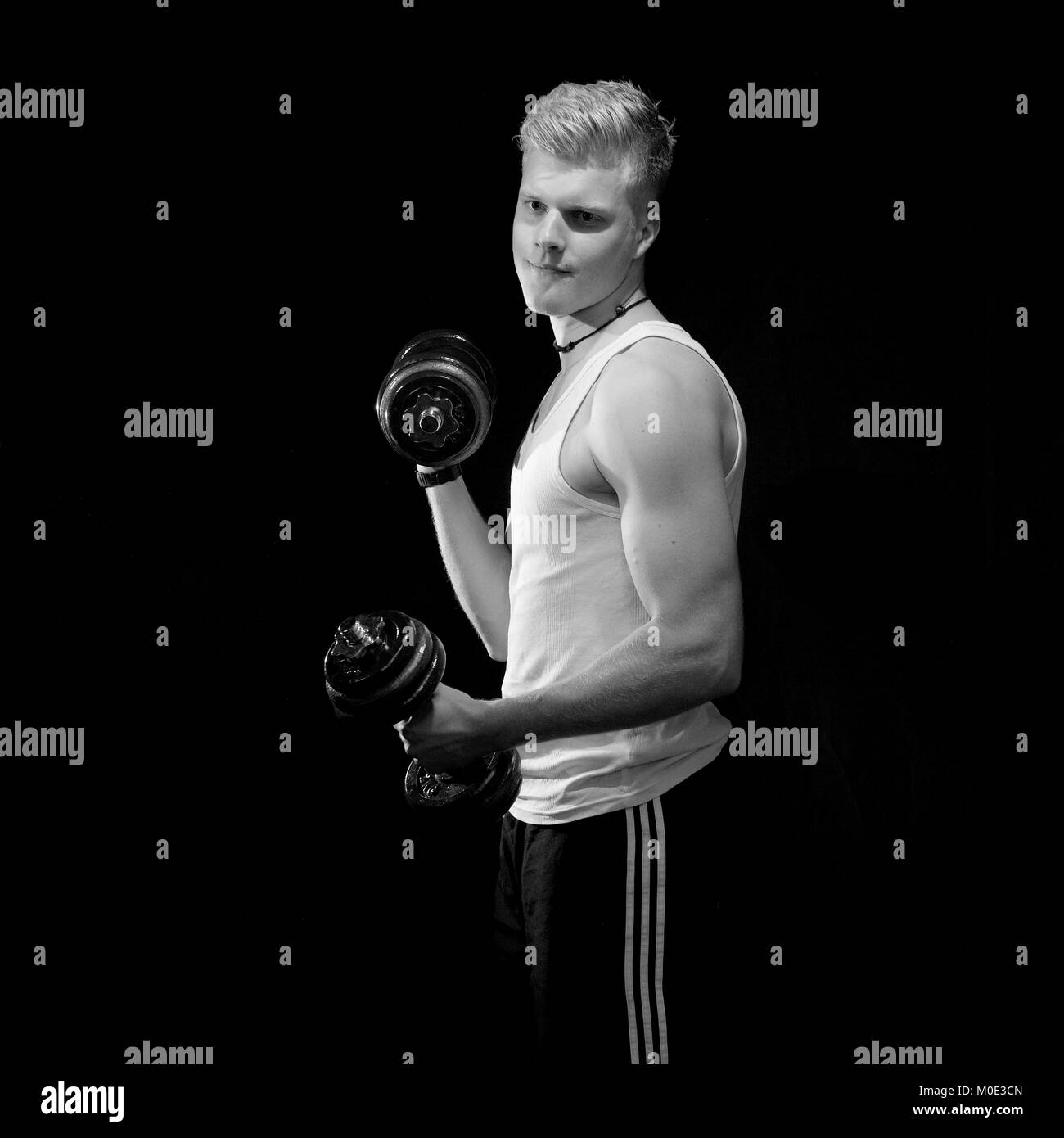 Young man keeping fit against a black background Stock Photo - Alamy