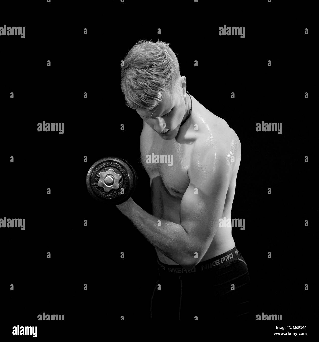 Young man keeping fit against a black background Stock Photo - Alamy