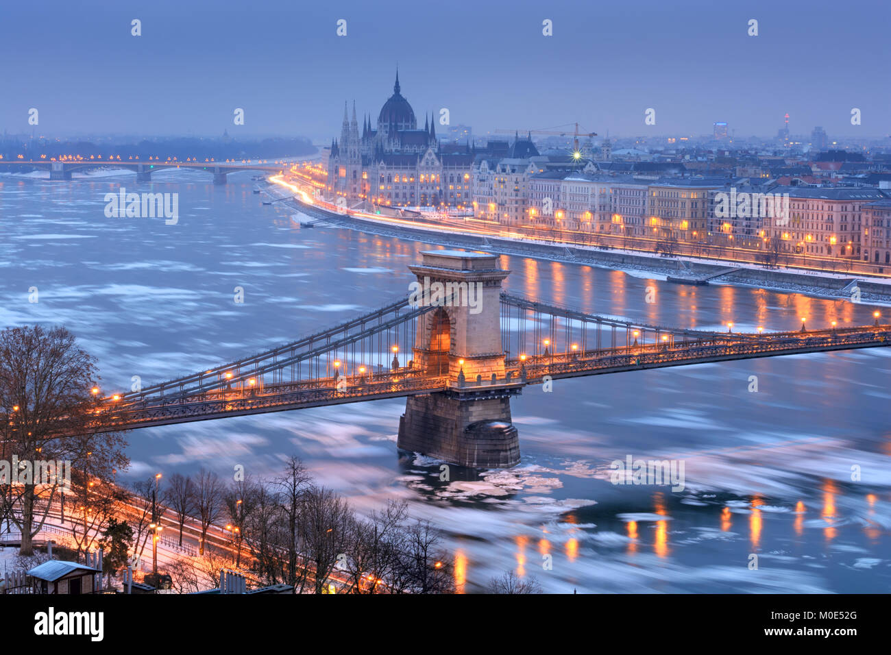 Szechenyi chain bridge and Pest riverfront with Parliament outline in ...