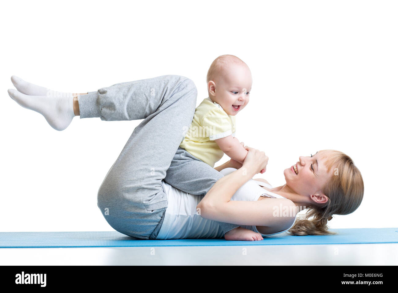 Young mother and baby are doing exercise and having fun isolated on a ...