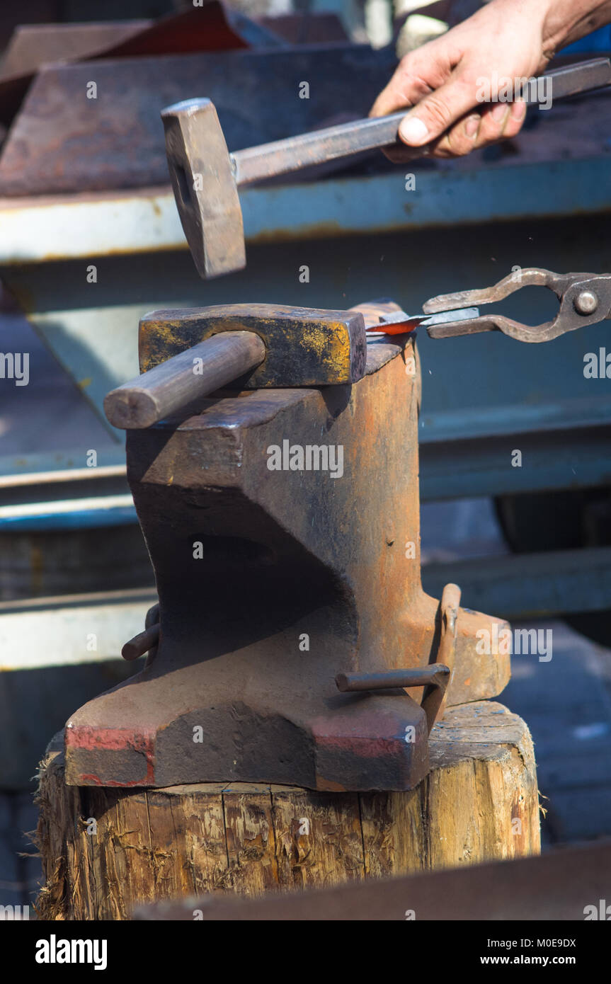 blacksmith performs the forging of hot glowing metal on the anvil Stock ...