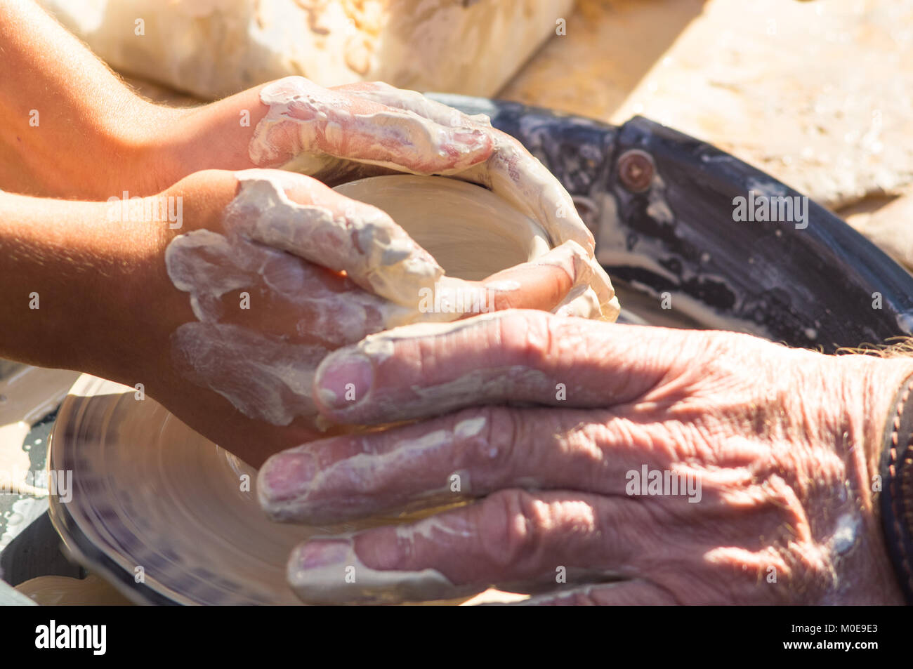 adult hand fed baby's hands to work with a potter's wheel Stock Photo ...