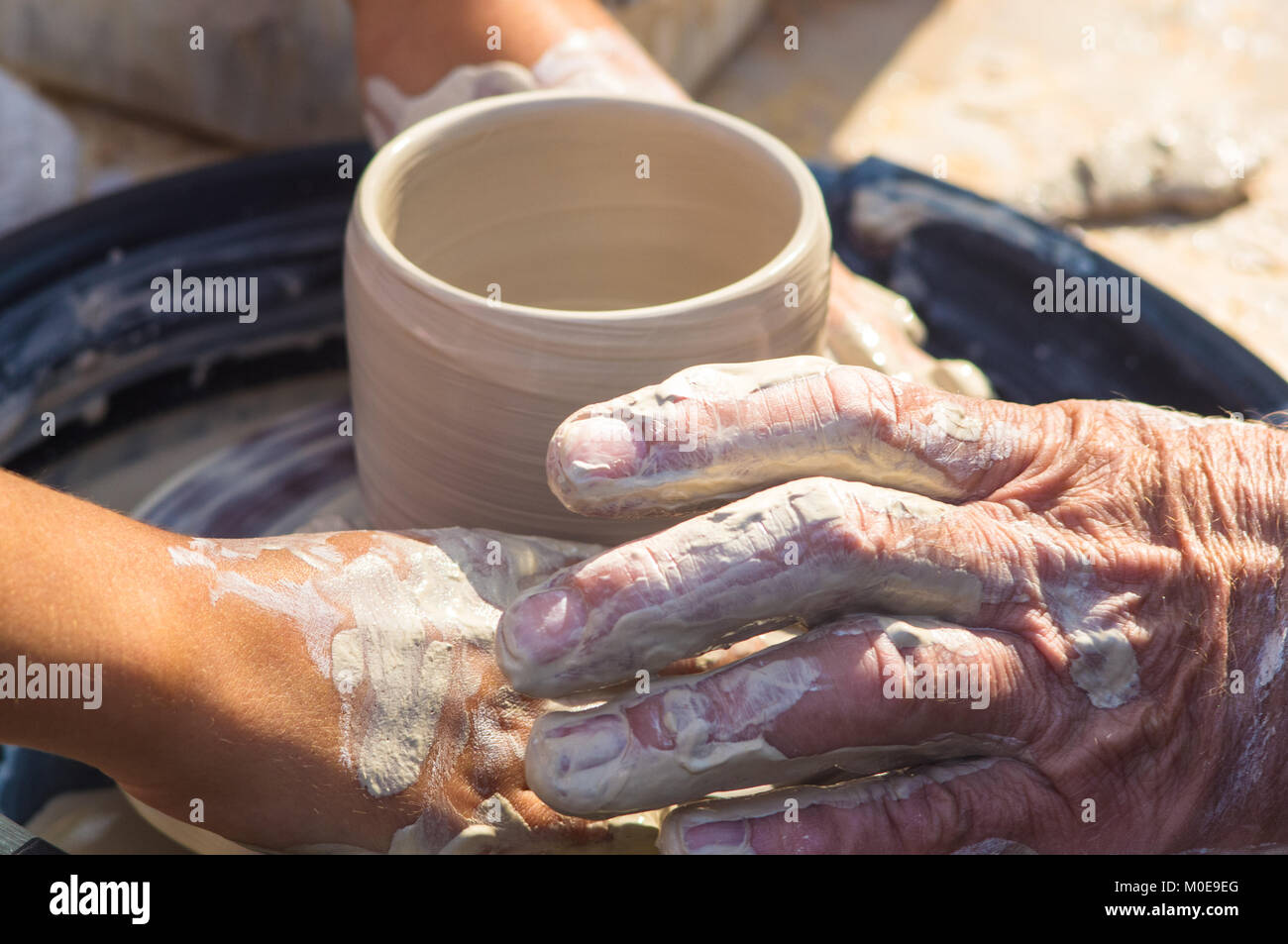 adult hand fed baby's hands to work with a potter's wheel Stock Photo ...