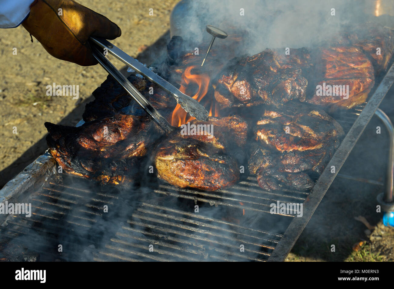 A flame sis flairing up as the fat from the meat is dripping on the hot ...