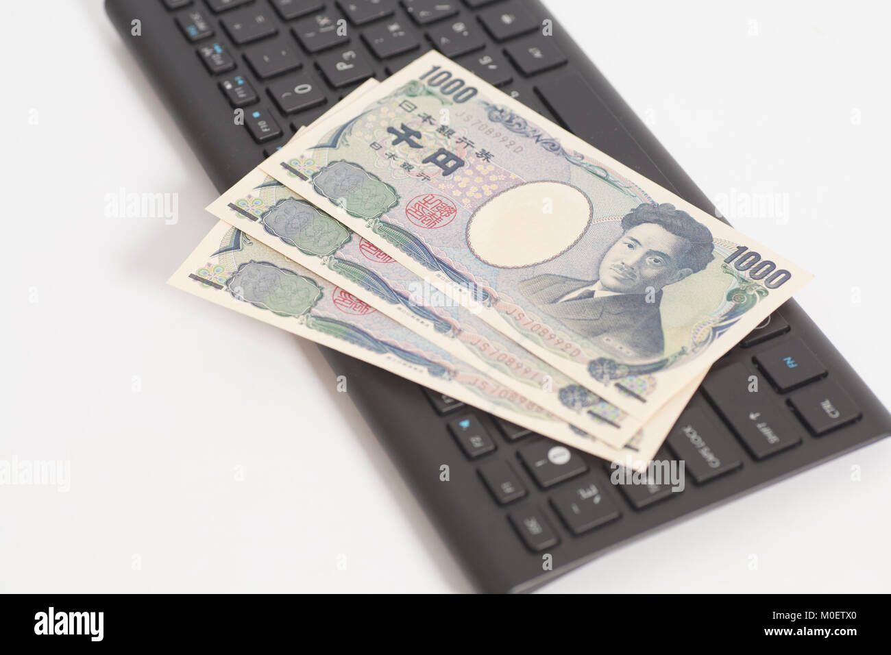 Japanese money one thousand yen on computer keyboard on white ...