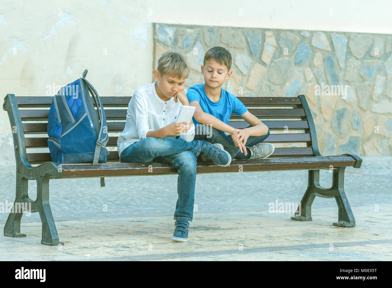 Boys with mobile phone sitting on the bench outdoors Stock Photo - Alamy