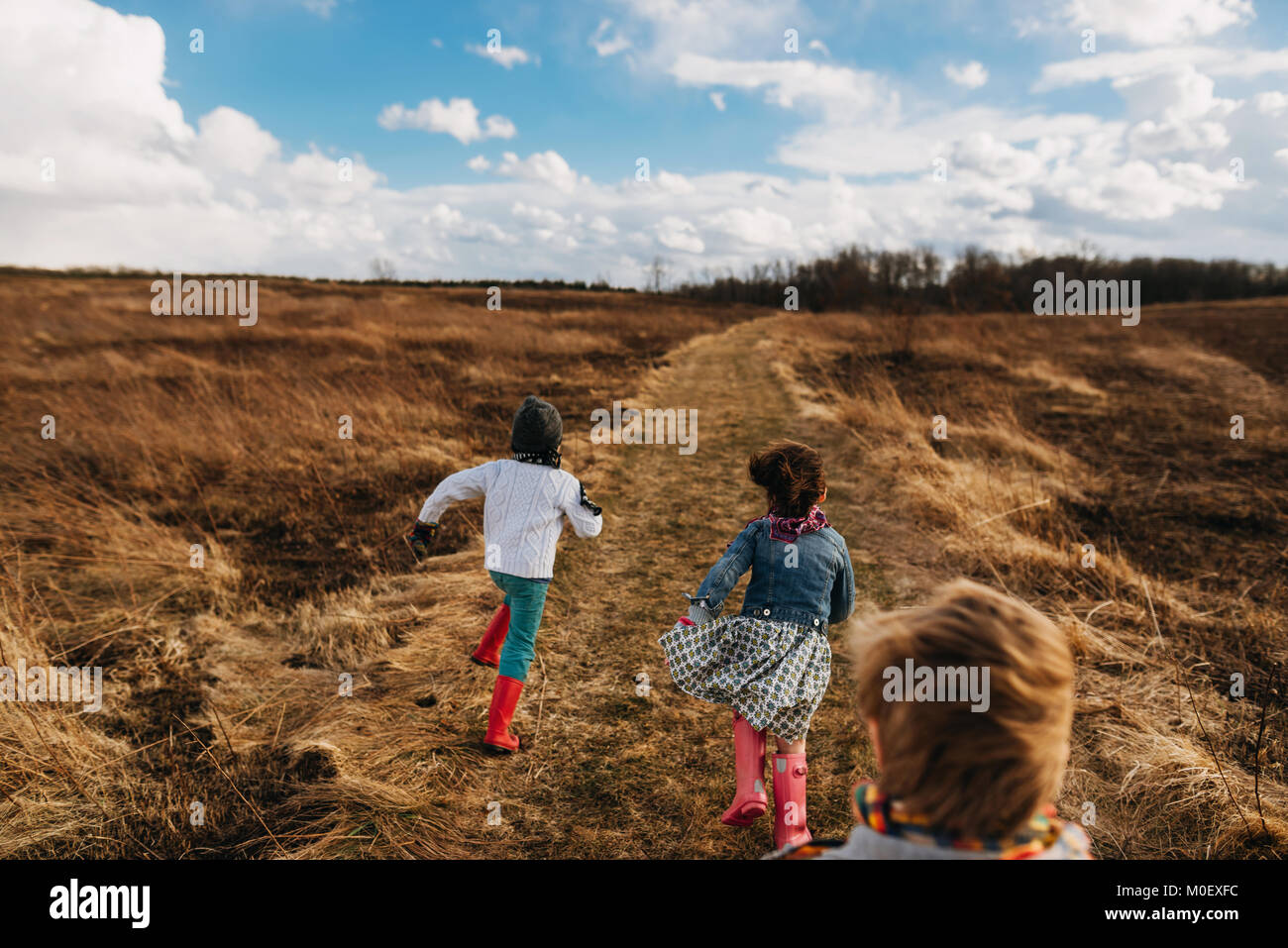 Three children running along a footpath in a rural landscape Stock ...