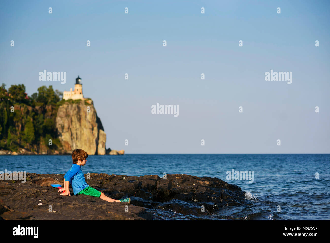 Boy sitting on rocks by a lake Stock Photo - Alamy
